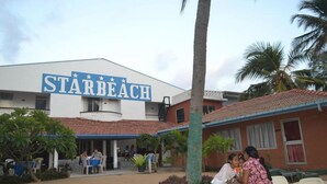 Edifício Starbeach com letreiro, mesas ao ar livre e palmeiras.