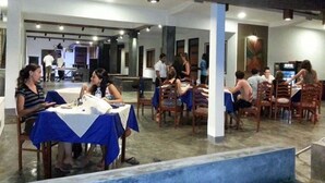 Restaurante com várias mesas e cadeiras, algumas cobertas por toalhas azuis.