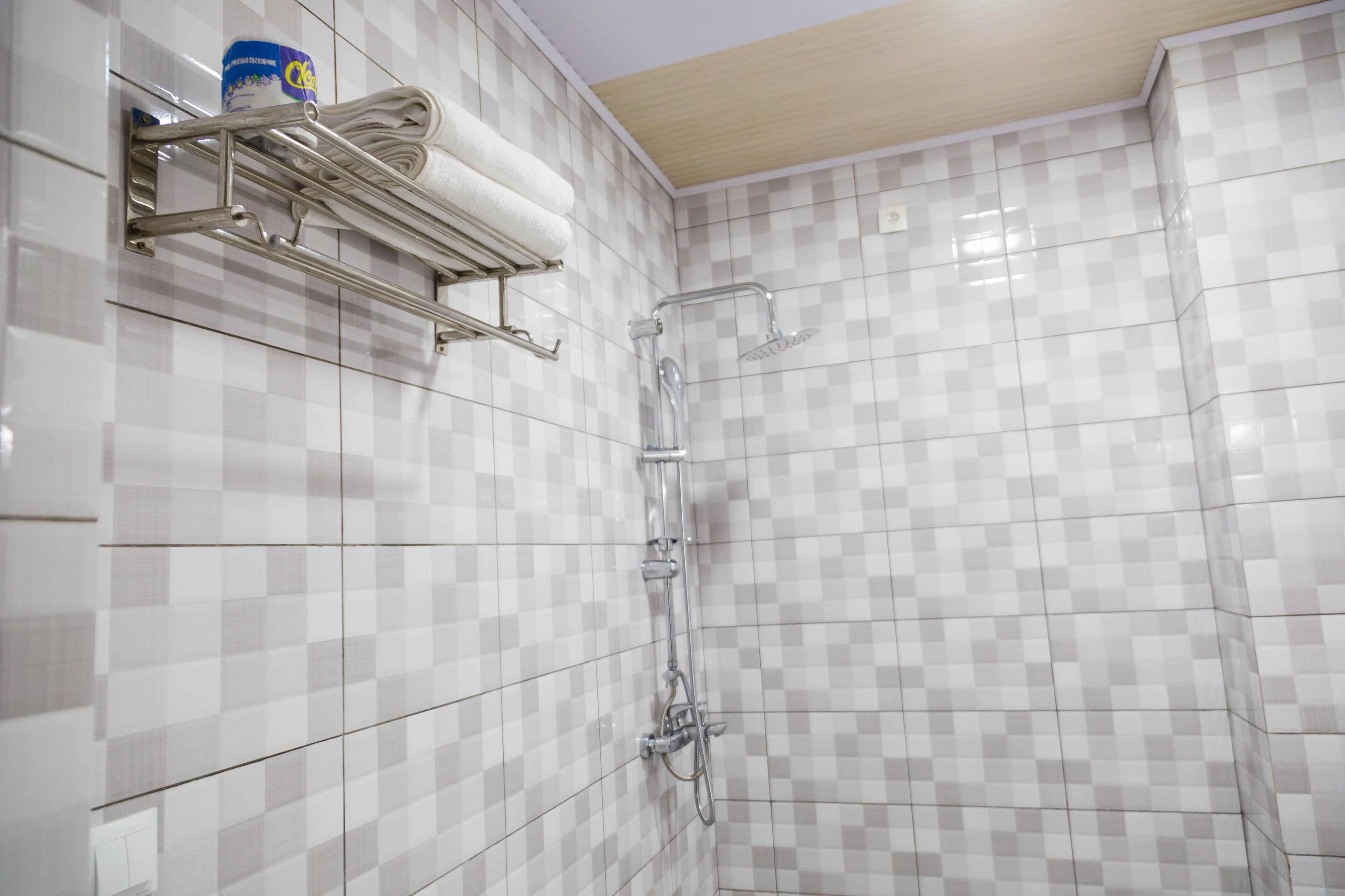 Casa de banho com azulejos xadrez, toalheiro e chuveiro.