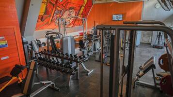 Uma academia com diversos equipamentos de exercícios, incluindo halteres e aparelhos de musculação.