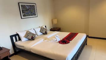 Cama bem arrumada com roupa de cama branca e almofadas decorativas, um corredor vermelho e um quadro na parede.
