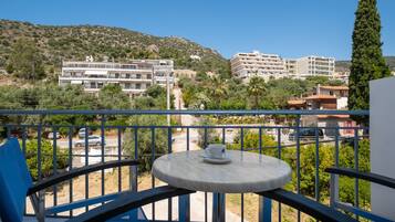 Uma varanda com uma mesa redonda e cadeiras, com vista para uma área residencial com edifícios e vegetação.
