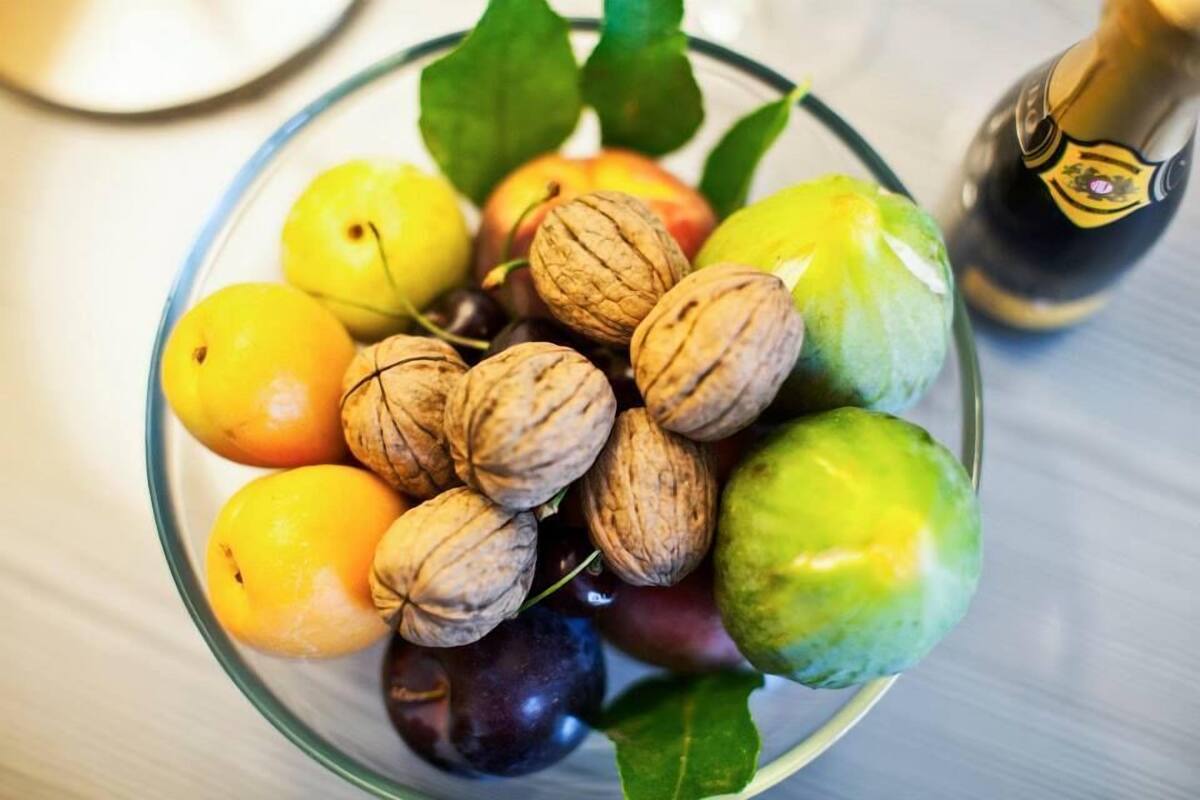 Uma tigela de vidro com frutas e nozes diversas.