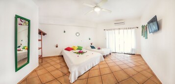Quarto com duas camas, ventoinha no teto, ar condicionado e janela com cortinas.