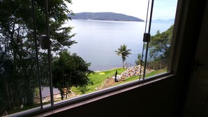 Vista de um lago pela janela, com um monte de rochas e um tapete amarelo na grama.