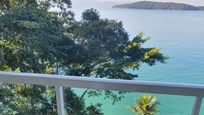 Varanda com mesa posta para o pequeno-almoço, com vista para um corpo de água e uma ilha ao longe.