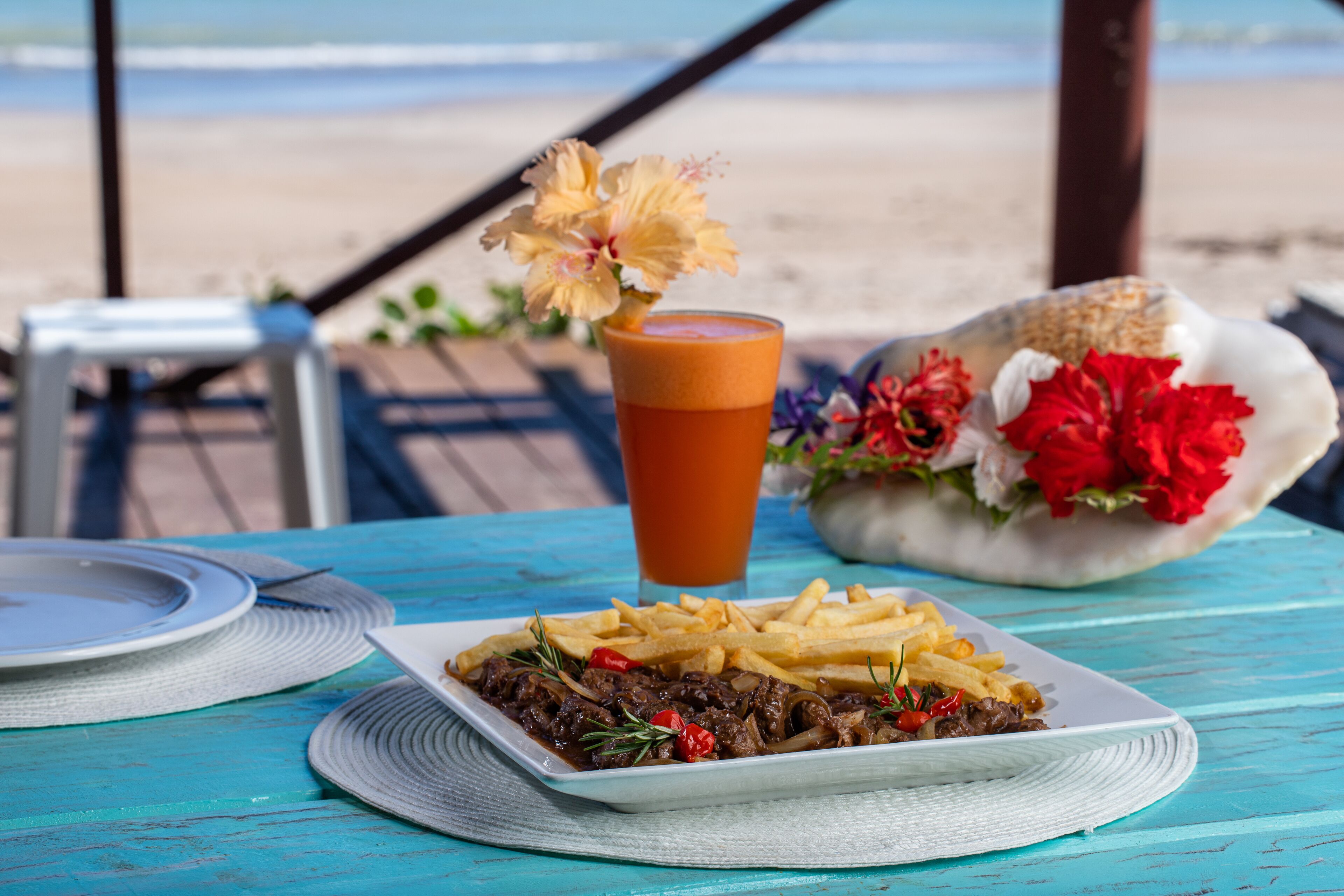 Uma mesa com um prato de comida, uma bebida e um arranjo floral decorativo.