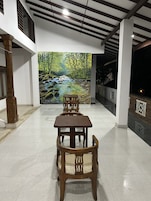 Uma área de refeições com mesa e cadeiras, um mural de um riacho em meio à floresta e vista para o exterior.
