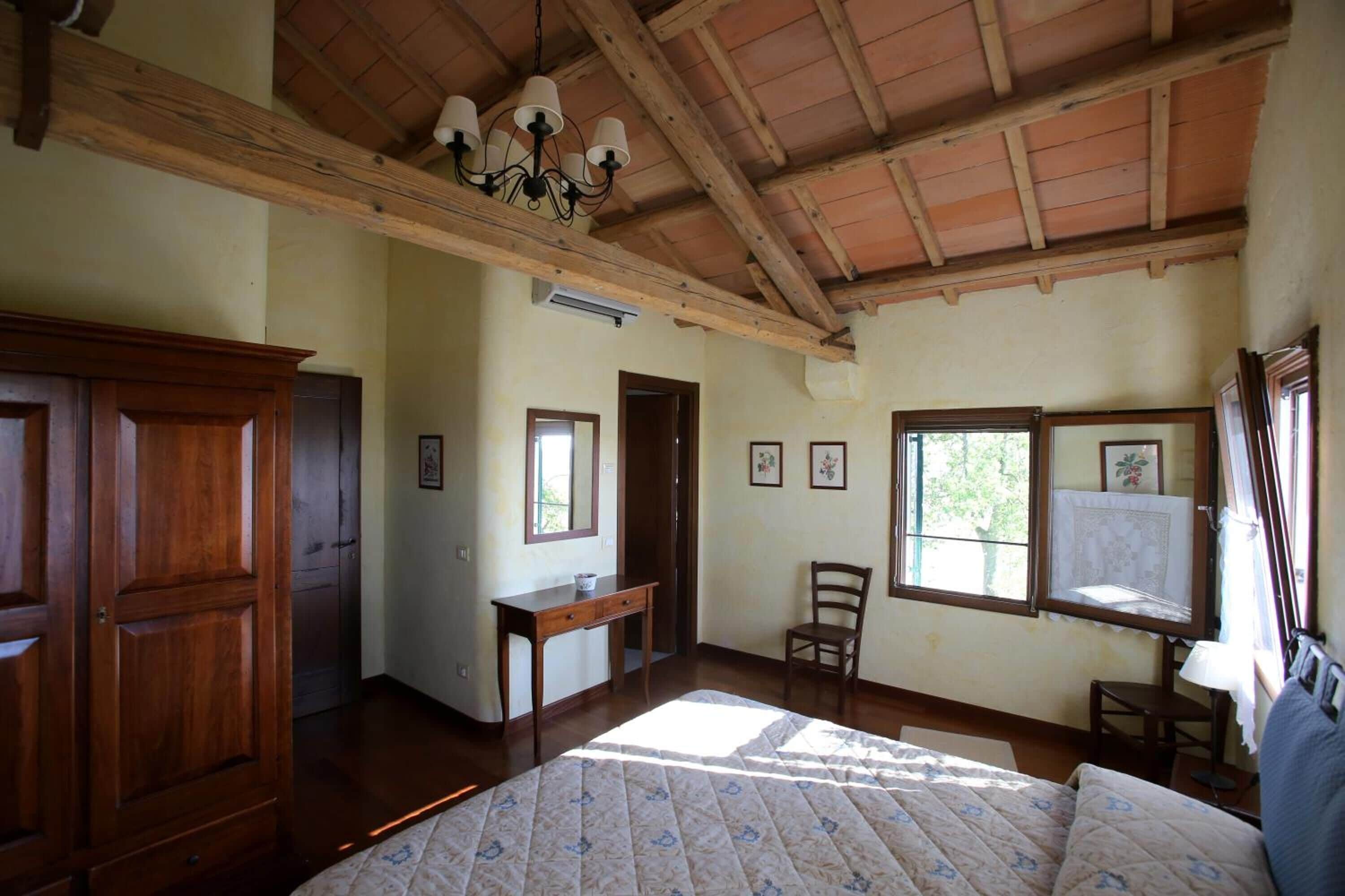Um quarto com uma cama grande, móveis de madeira, uma escrivaninha e uma cadeira.