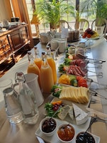 Um buffet de café da manhã com diversas opções de comida, bebidas e utensílios.