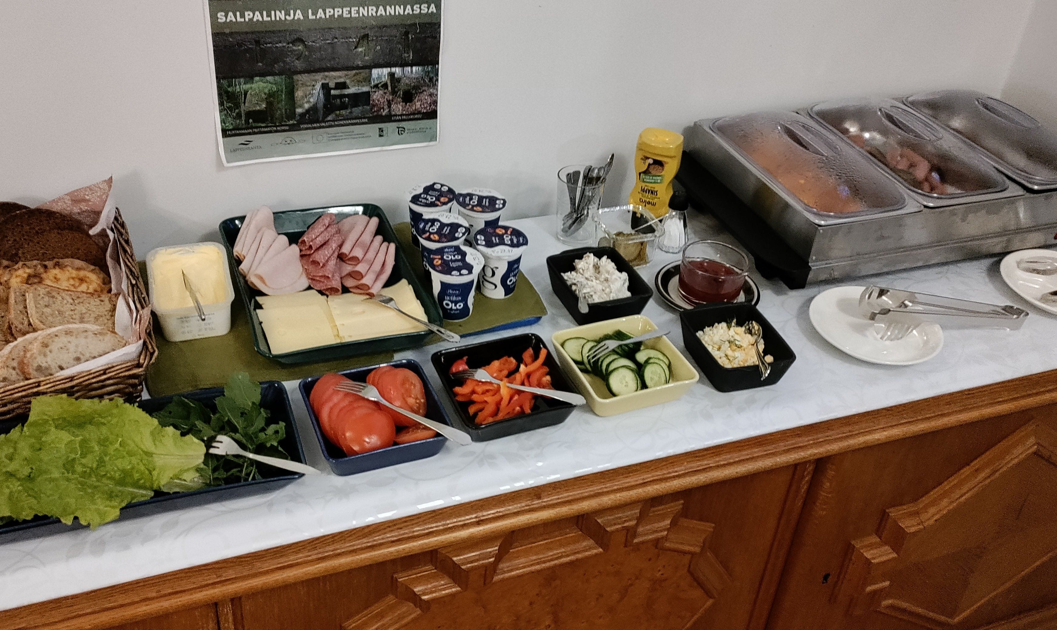Buffet com diversas opções de comida, incluindo pão, queijo, carnes e saladas.