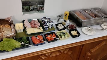 Buffet com diversas opções de comida, incluindo pão, queijo, carnes e saladas.