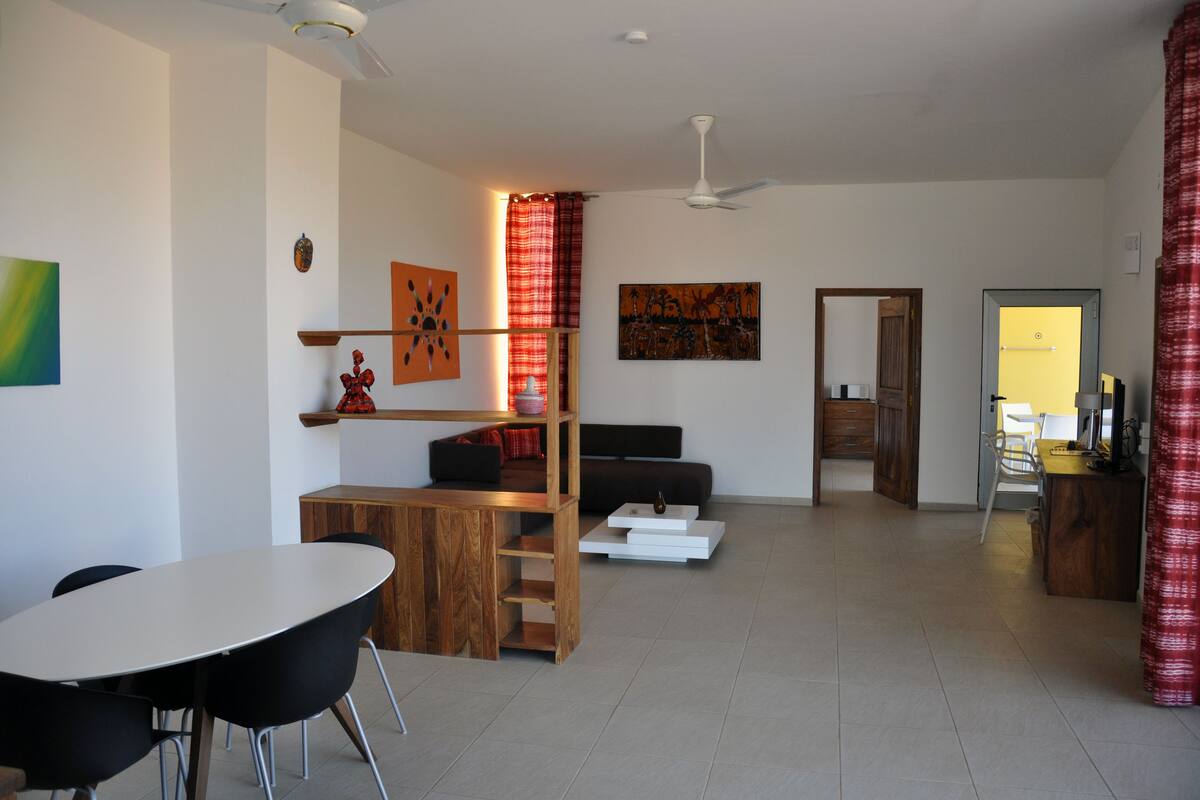 Uma sala de estar moderna com área de jantar, escada e cozinha.