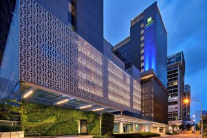 Um edifício moderno com fachada estampada, entrada visível e parede verde com plantas.