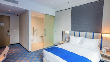 Quarto de hotel com cama, mesa de cabeceira e banheiro com chuveiro.