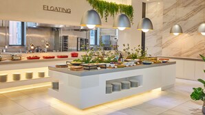 Uma cozinha moderna com painel de fundo de mármore, uma ilha central com serviço de buffet e luminárias pendentes.