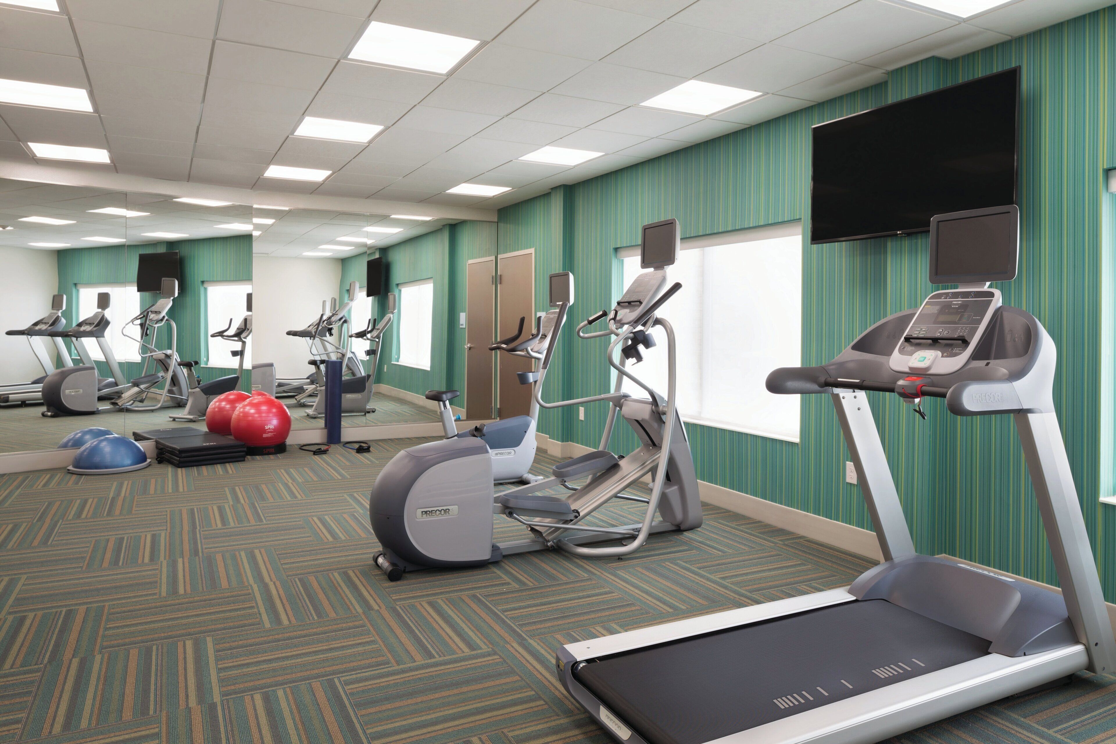 Academia com esteiras, elípticos e bolas de exercício.