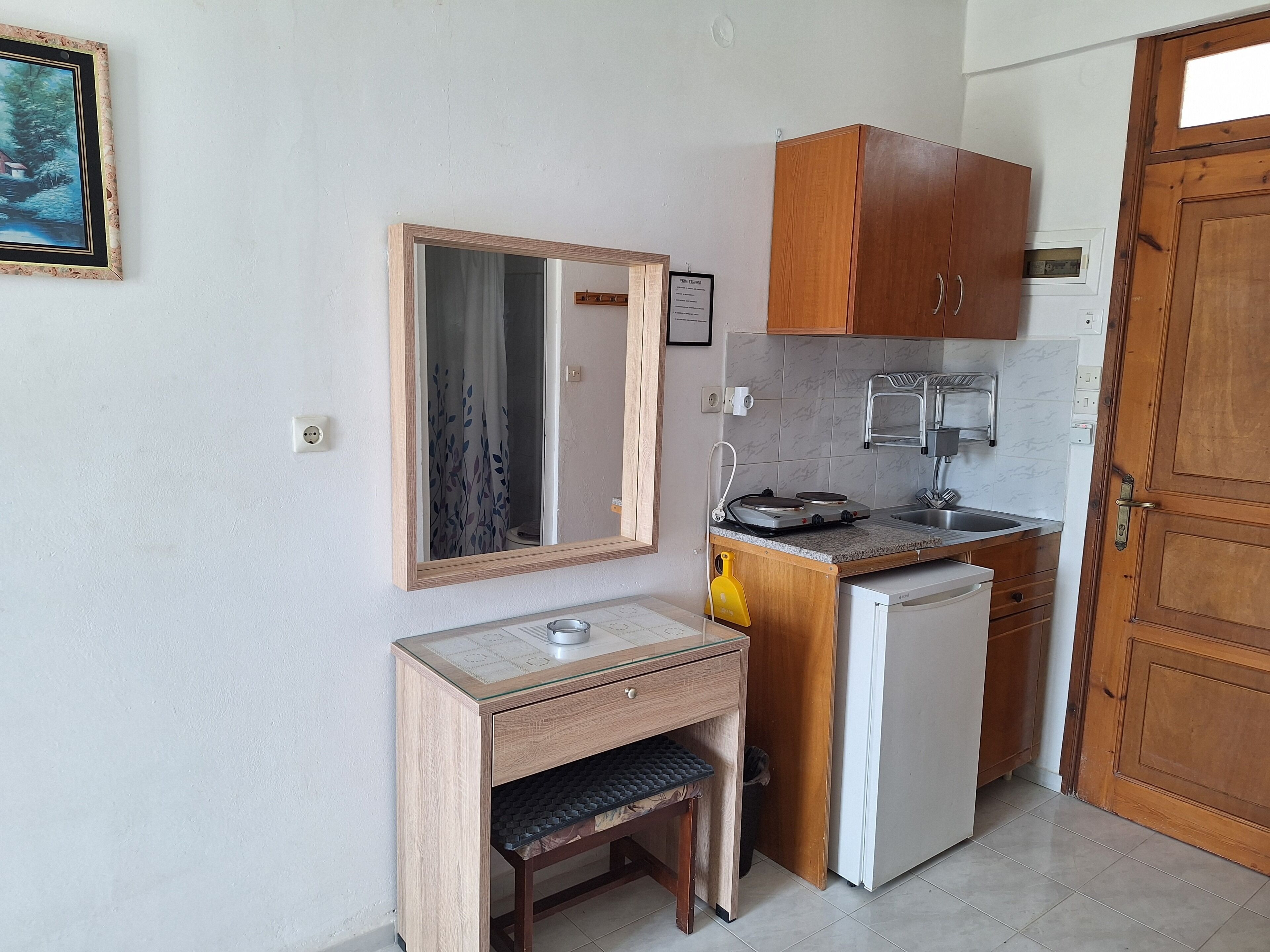 Cozinha compacta com geladeira, pia e armários de madeira.