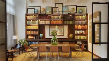 Uma biblioteca com estantes de livros, uma mesa de madeira e cadeiras.