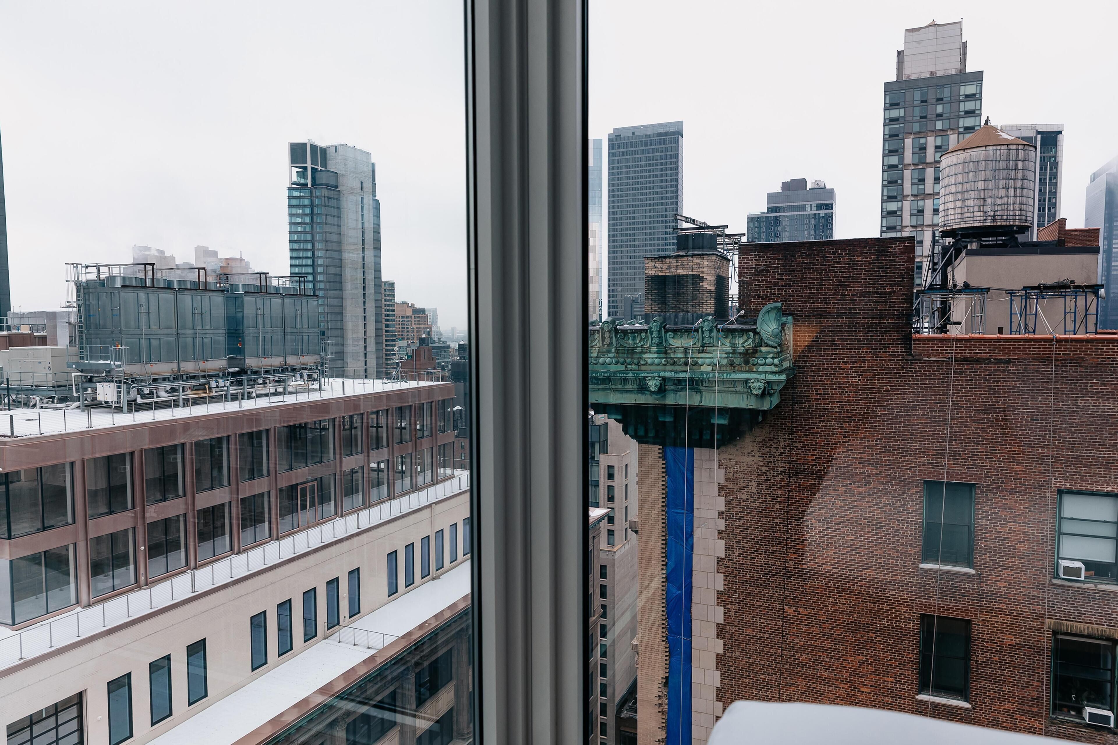 Paisagem urbana com edifícios modernos, uma grande estrutura industrial e um prédio de tijolos com uma faixa azul.