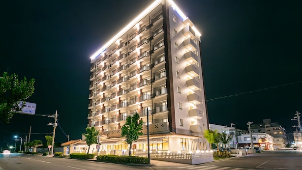 Um hotel com vários andares, varandas, restaurante no térreo e fachada bem iluminada.