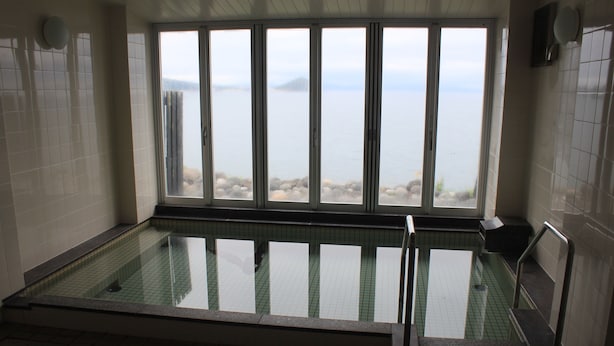 Piscina com vista para o mar através de grandes janelas.