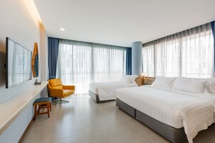 Quarto de hotel com duas camas, televisão, escrivaninha e uma cadeira.
