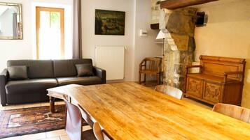 Uma sala de estar com uma mesa de jantar de madeira, um sofá e uma parede de pedra.