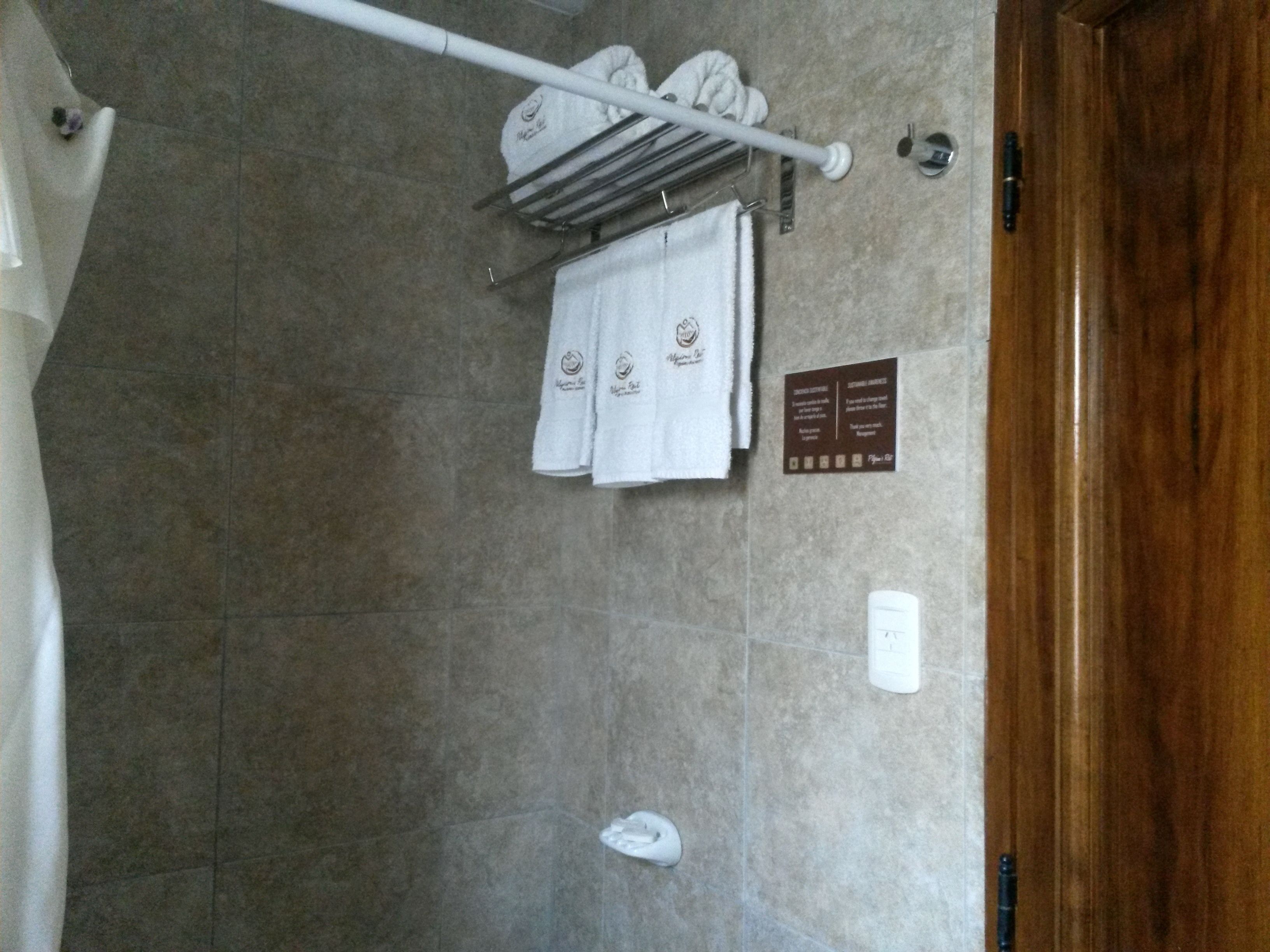 Casa de banho com um porta-toalhas com dois toalhas, um secador de mãos e um sinal com instruções.