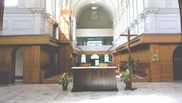 Um amplo interior com teto abobadado alto, painéis de madeira e um balcão de recepção central.