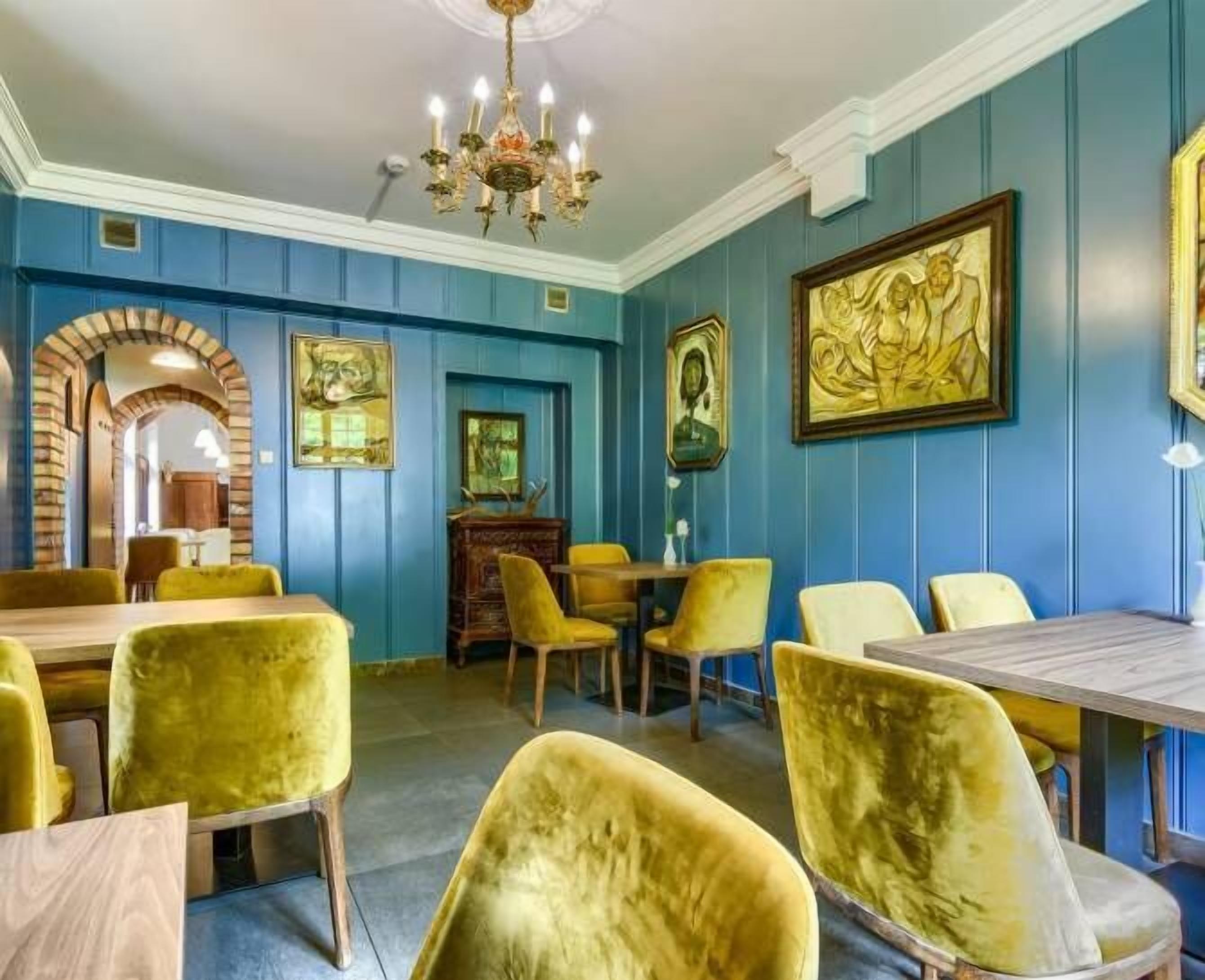 Uma sala de jantar com paredes revestidas de azul, cadeiras amarelas e um lustre.