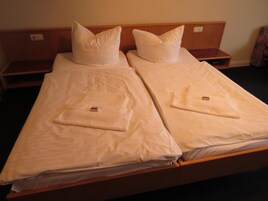 Uma cama de casal com duas almofadas e um cobertor dobrado.