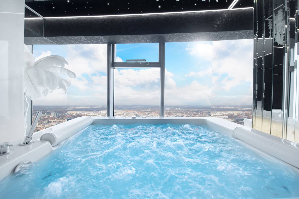Uma banheira de hidromassagem com vista para a cidade, grandes janelas e design moderno.