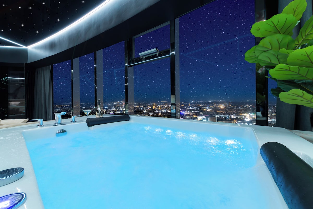 Piscina interior moderna com vista para a cidade à noite.