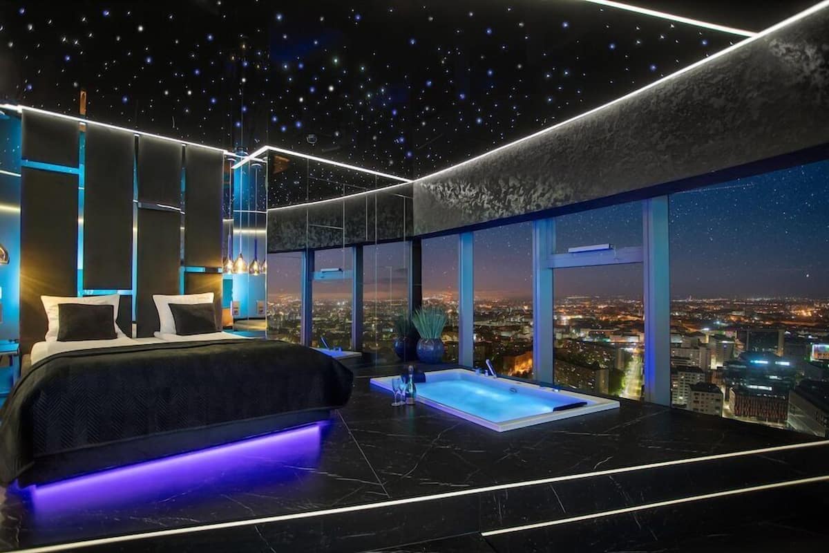 Quarto moderno com cama, banheira e vista para a cidade.