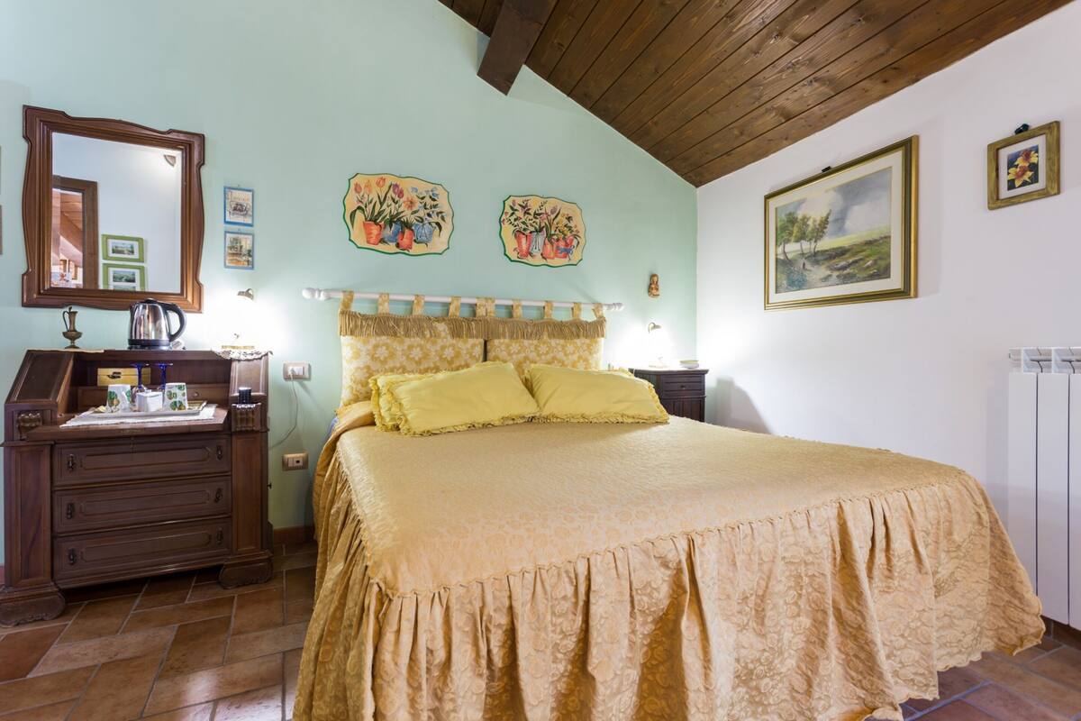 Quarto com cama, cómoda de madeira e radiador.