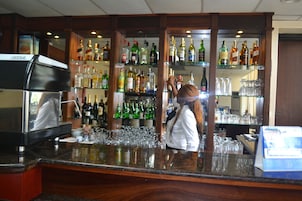 Uma área de bar com prateleiras de garrafas de bebidas e copos.