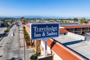 Placa de um Travelodge Inn & Suites, com vista para a rua e edifícios ao fundo.