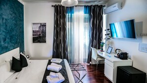 Quarto de hotel com cama, escrivaninha e televisão.