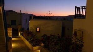 Um pátio com um pequeno edifício, uma escadaria e vista para o pôr do sol.