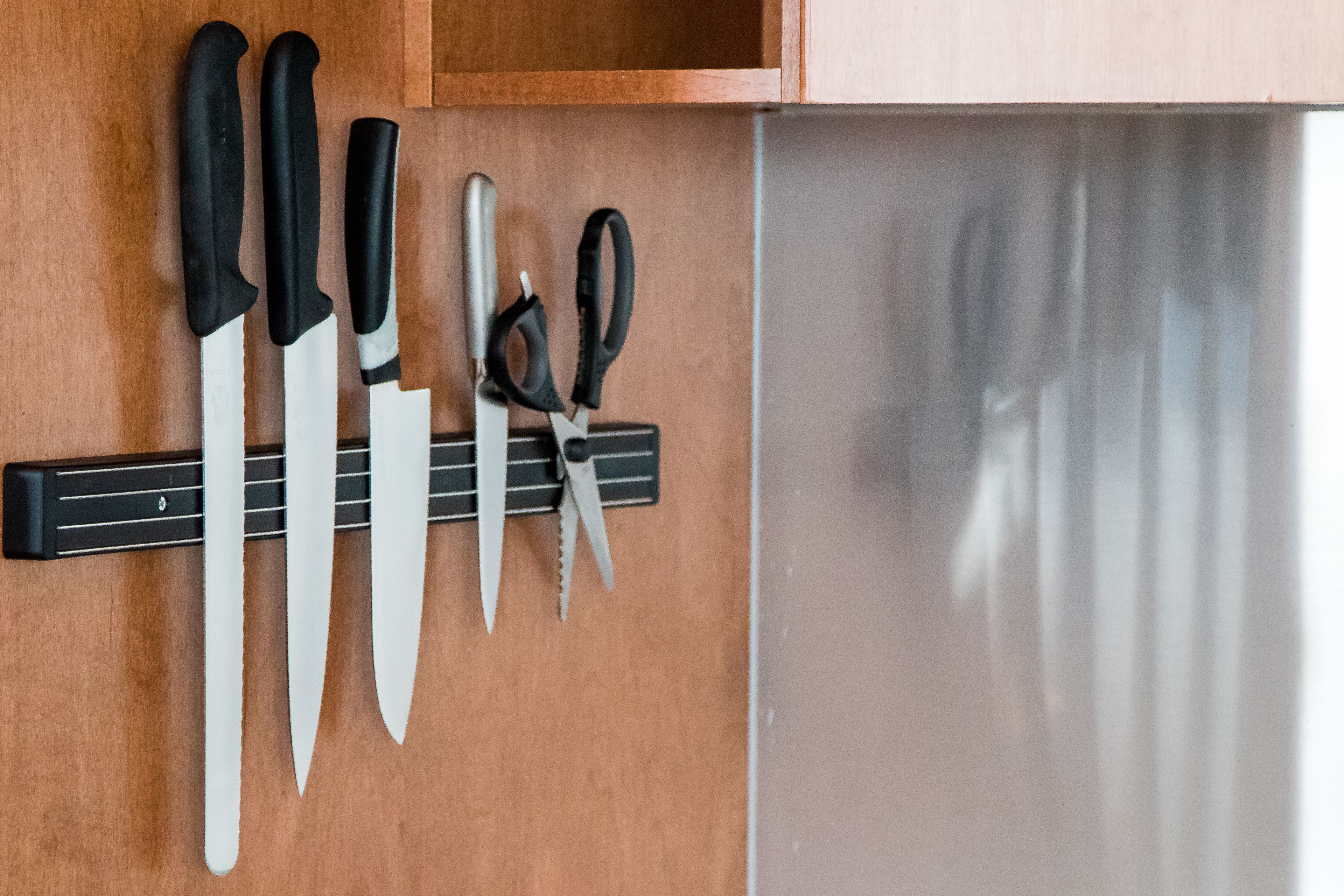 Cozinha com facas e tesouras fixadas em suporte preto.