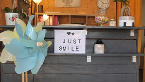 Uma receção com o letreiro 'Just Smile', painéis de parede de madeira, um relógio e vários objetos decorativos.