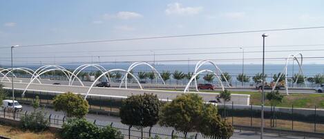 Uma ponte moderna com arcos brancos, uma estrada com carros e um corpo d'água ao fundo.