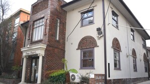 Um edifício de dois andares com fachada de tijolos, seção superior branca e uma placa com a inscrição 'Cox Court Budget Accountants'.