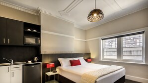 Quarto de hotel moderno com cama, mesas de cabeceira, micro-ondas embutido, mini-geladeira e janela com vista.