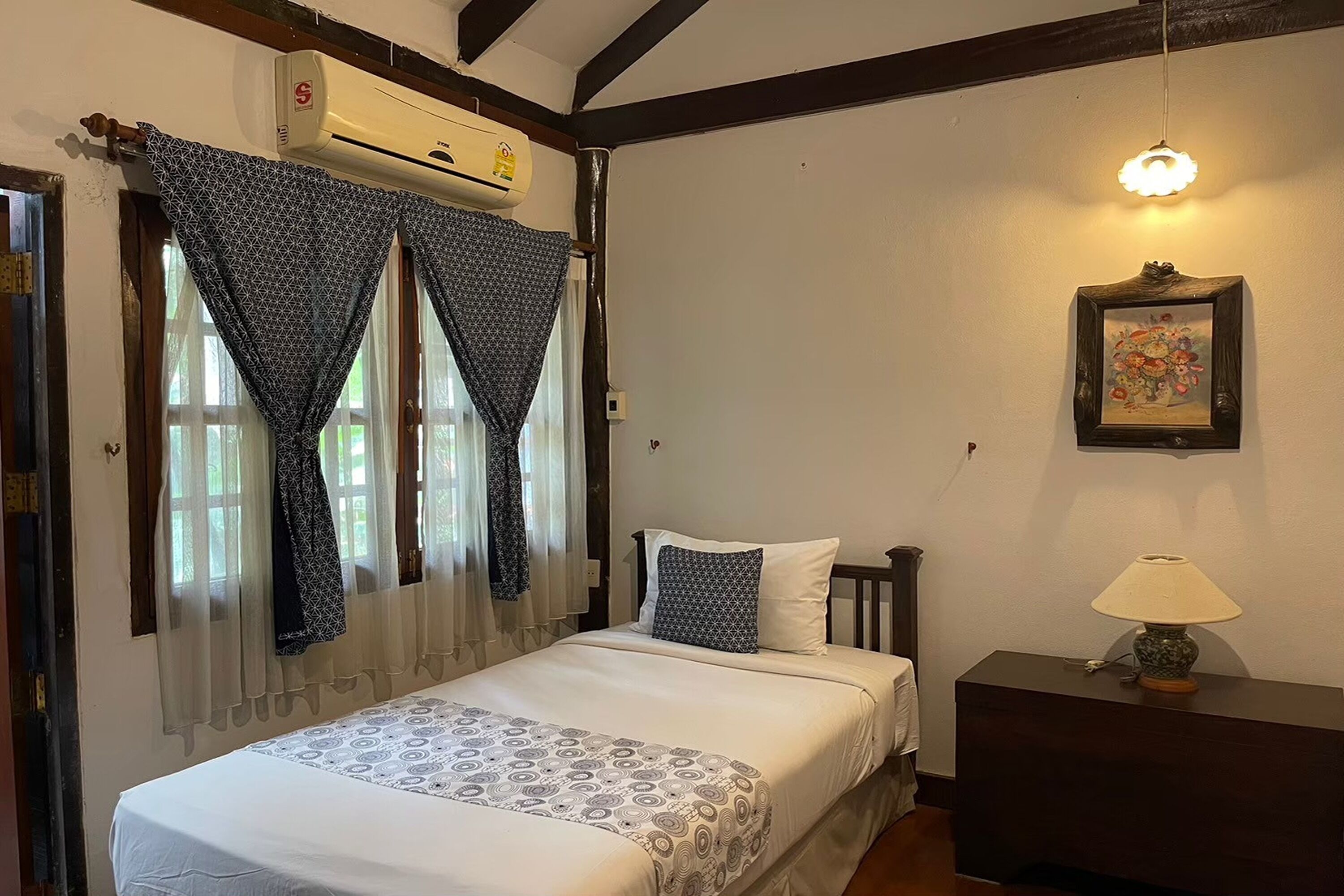 Um quarto com uma cama, uma mesa de cabeceira, um abajur e um quadro na parede.