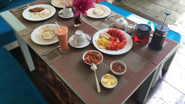 Mesa de café da manhã com pratos de comida, bebida e acompanhamentos.