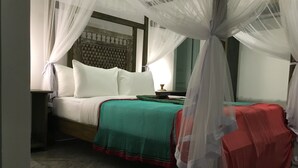 Quarto com cama sob dossel, mesa de cabeceira e criado-mudo com abajur.