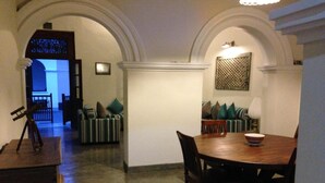 Uma sala de jantar com mesa e cadeiras de madeira, um sofá com almofadas listradas e um telescópio em um suporte.