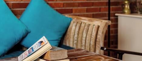 Uma mesa de madeira com livros e uma lâmpada em frente a uma parede de tijolos.